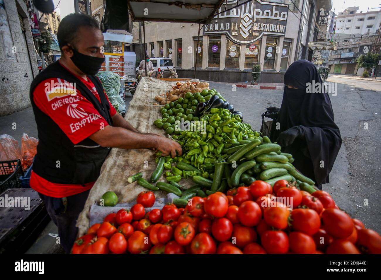 A Palestinian vegetable vendor wearing a face mask in Khan Yunis ...