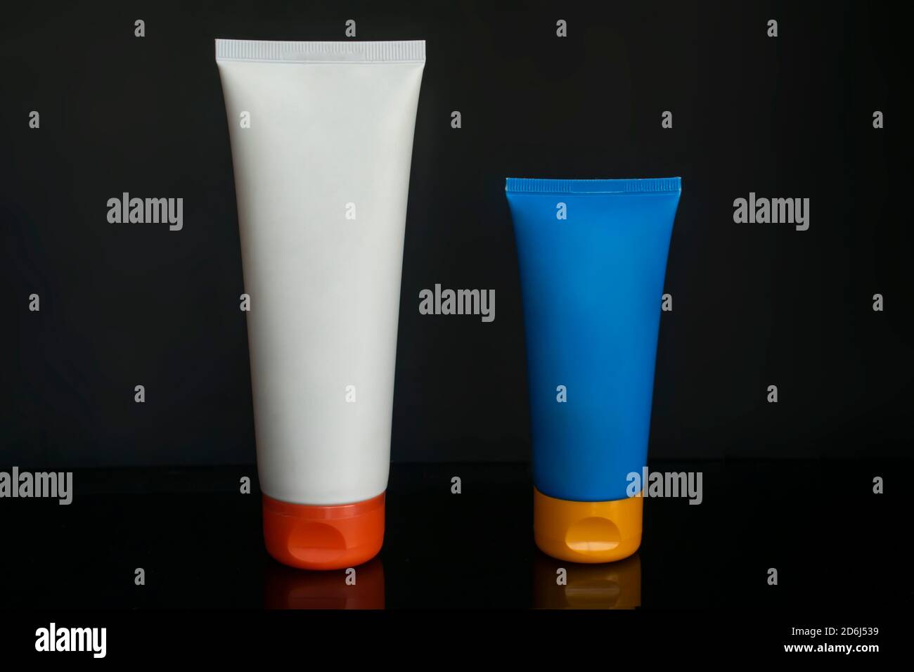 white and blue packaging for cream and lotion over black background ...