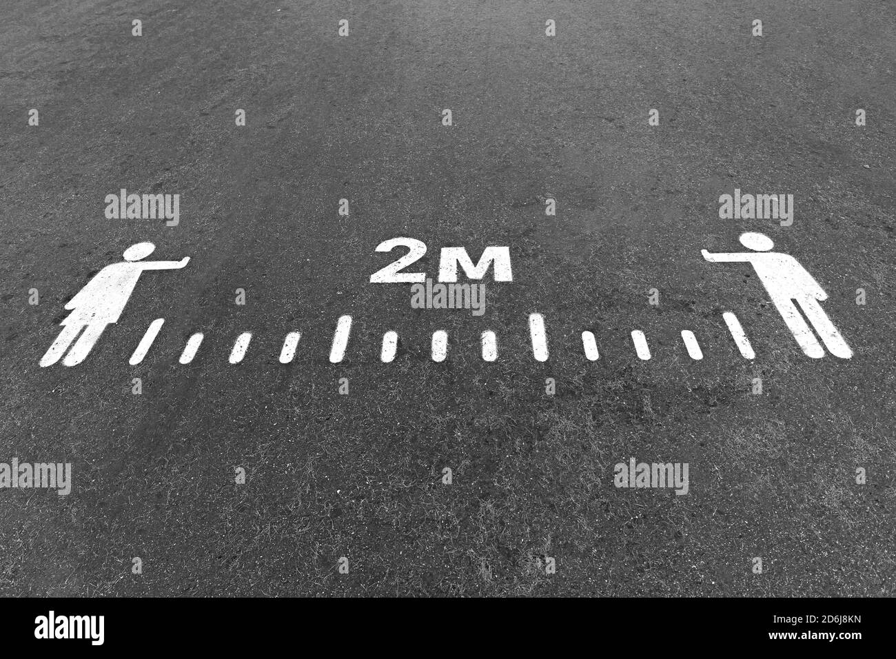 White painted 2 meters social distance sign on an asphalt road ...