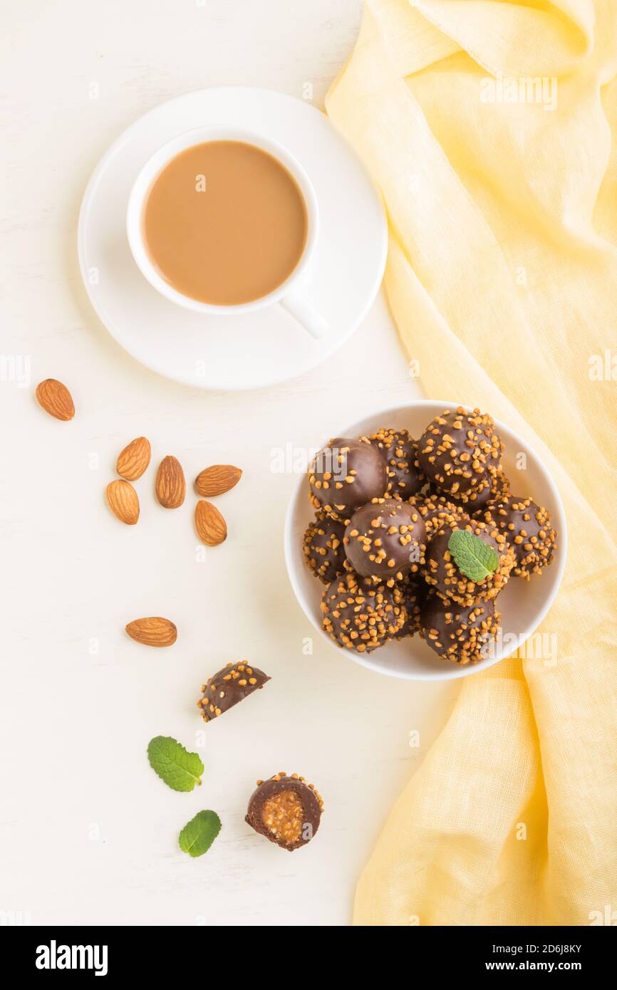 Chocolate caramel ball candies with almonds and a cup of coffee on a ...