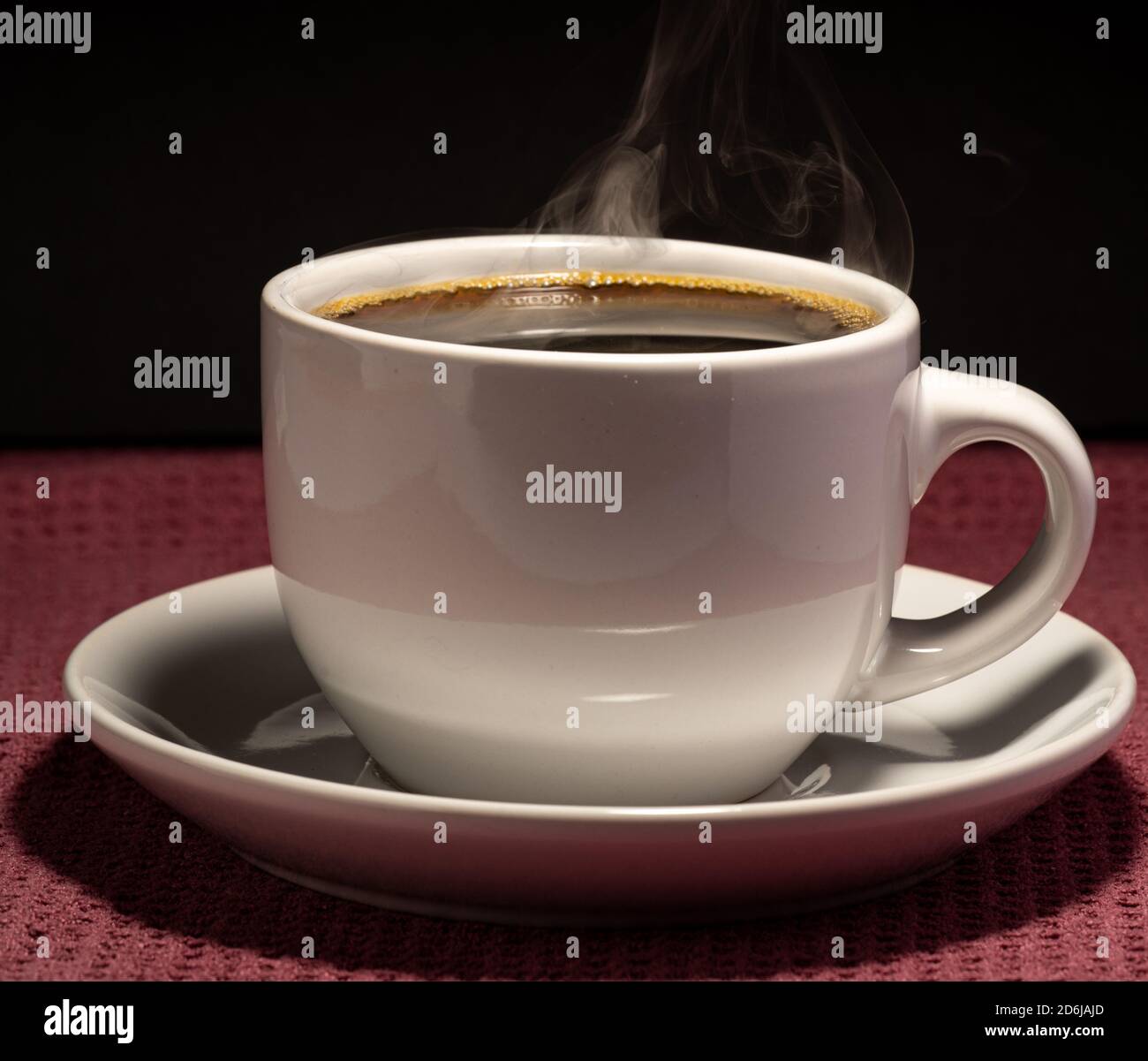 Coffee steaming in a cup with saucer isolated on a black background on ...