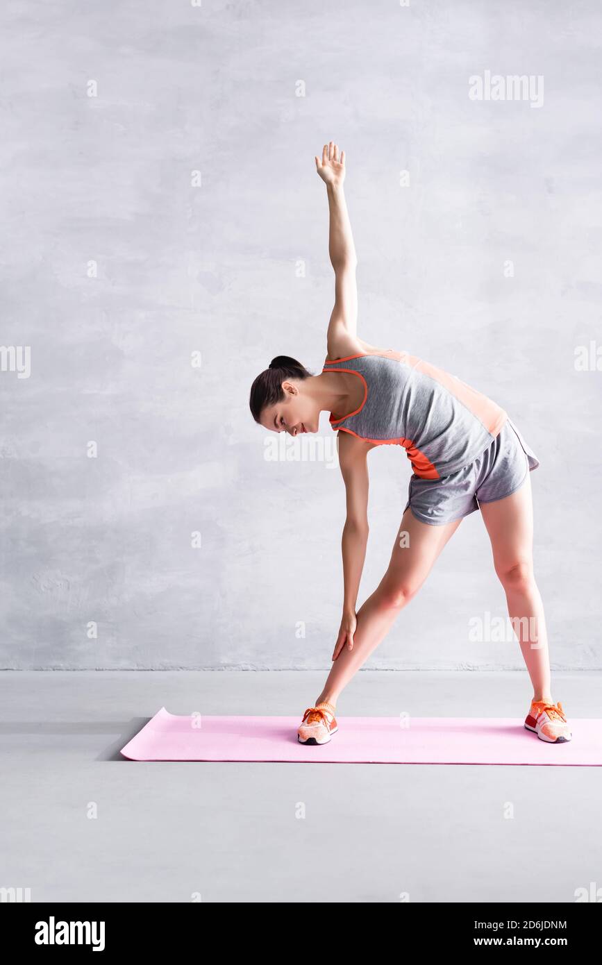 Sportswoman with outstretched hands stretching on grey background Stock ...