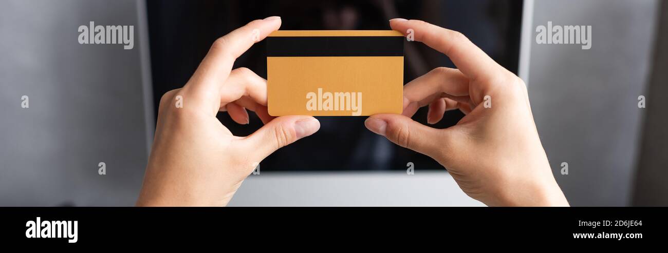 Horizontal image of woman holding credit card near computer monitor at ...