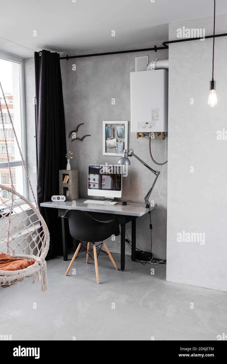 Spacious workplace interior with computer and hanging chair Stock Photo ...