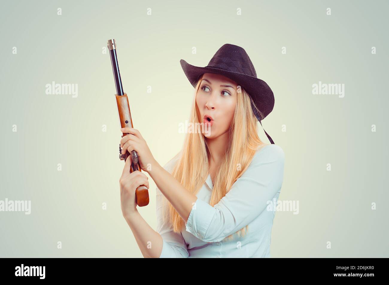 Modern blond woman in cowboy hat holding and recharging her gun before ...