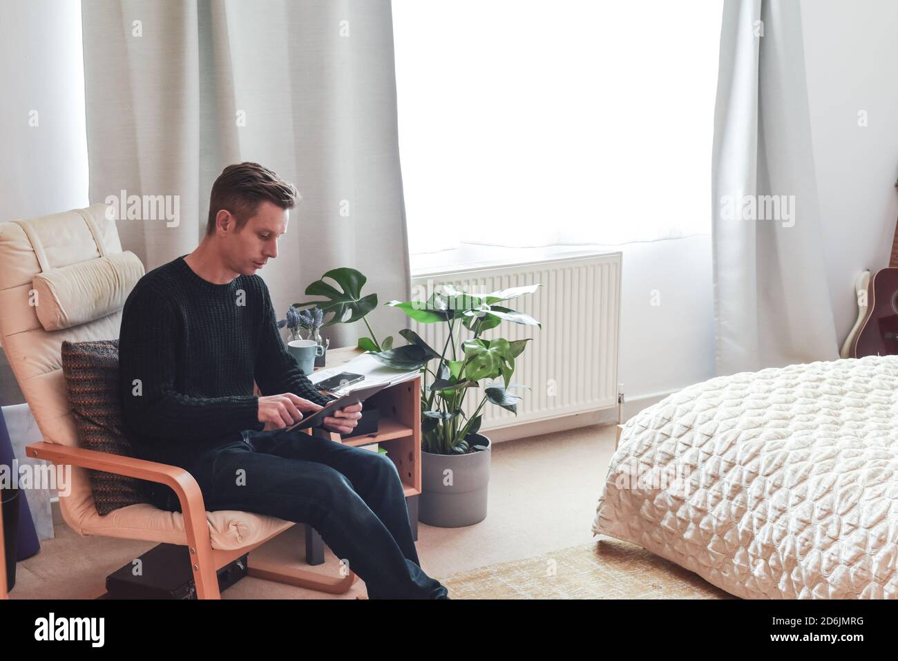 A man uses a wireless tablet device at home to check email and social ...