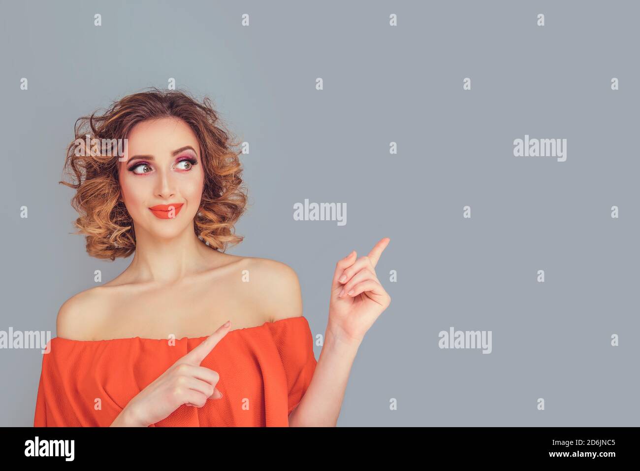 Look here. Happy smiling beautiful young woman showing pointing hands ...