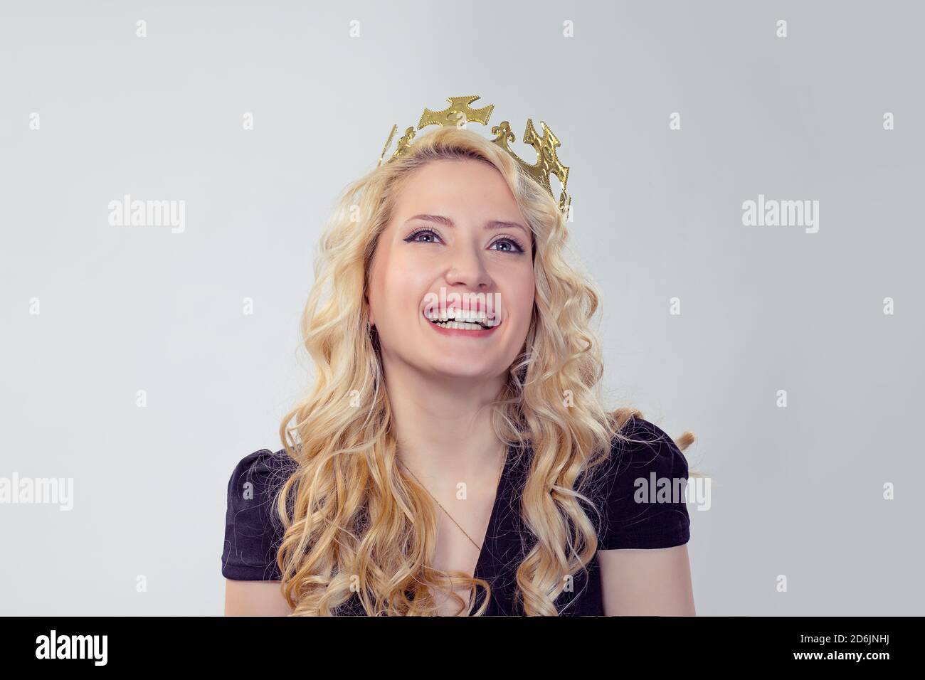 Adorable blond woman wearing golden crown and smiling laughing happily ...