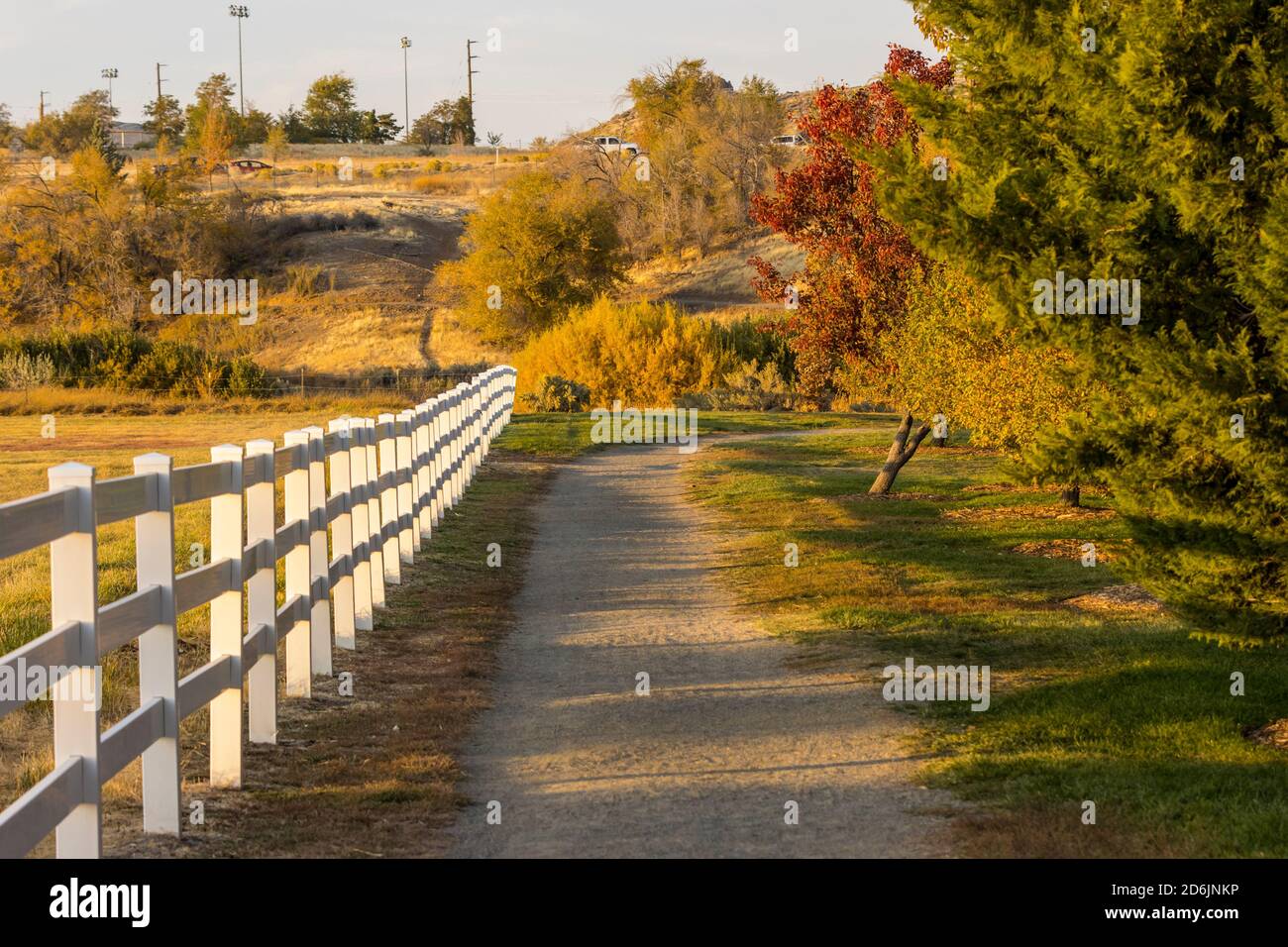 Running trail through a park along a white fence lined with trees Stock ...