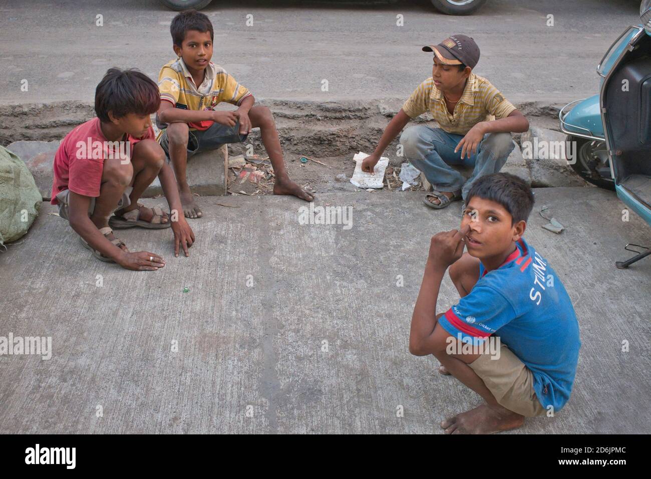 A group of homeless street boys passing their time sitting in a street ...