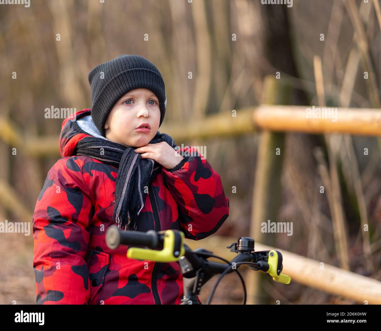 Sad, angry kid with hat and scarf sitting on bicycle at park Stock ...