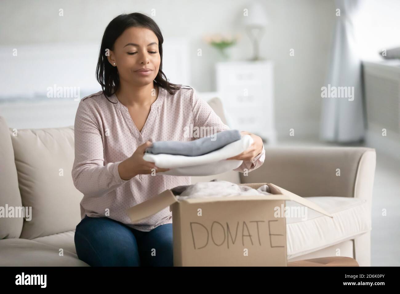 Caring biracial woman gather clothes in donation box Stock Photo - Alamy