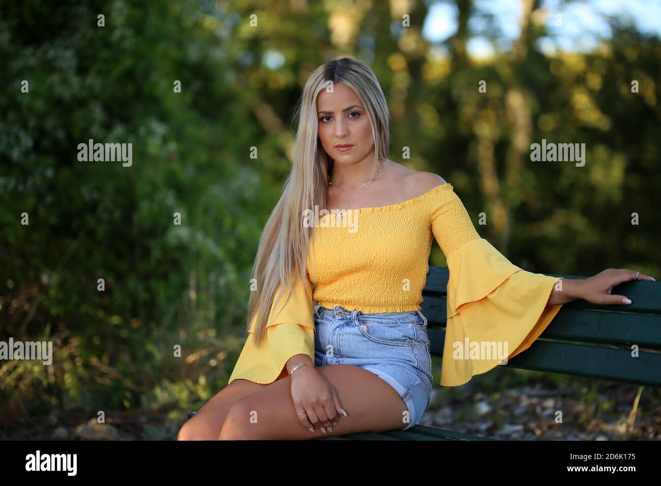 Portrait of a young girl sitting on a bench Stock Photo - Alamy