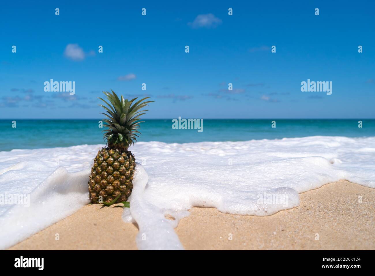 Pineapple on sand with sea water splash on blue sky summer concept ...