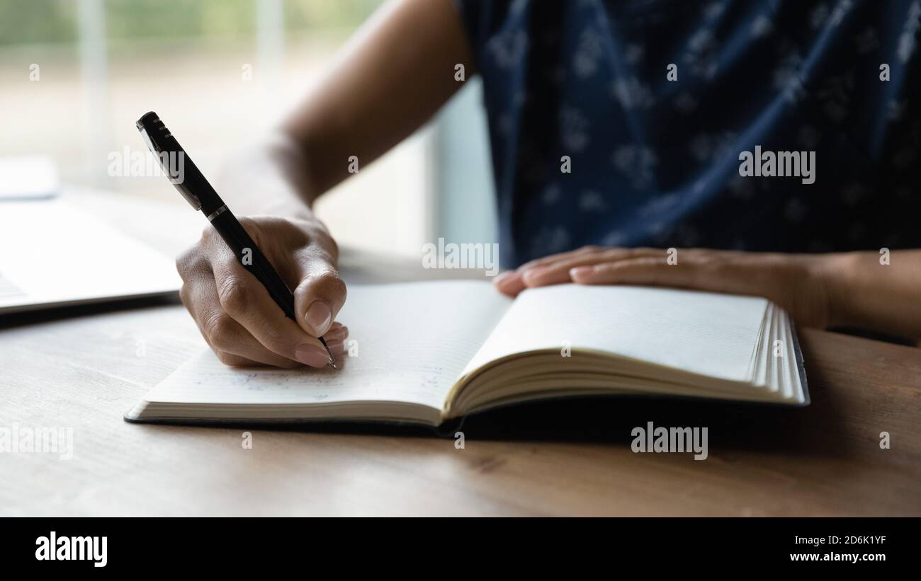 Crop of woman writing in notebook making plans Stock Photo - Alamy