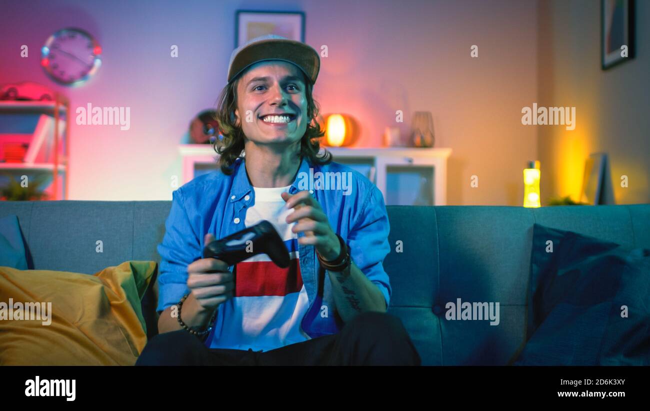 Handsome Excited Young Gamer with Long Hair and a Cap is Sitting on a ...