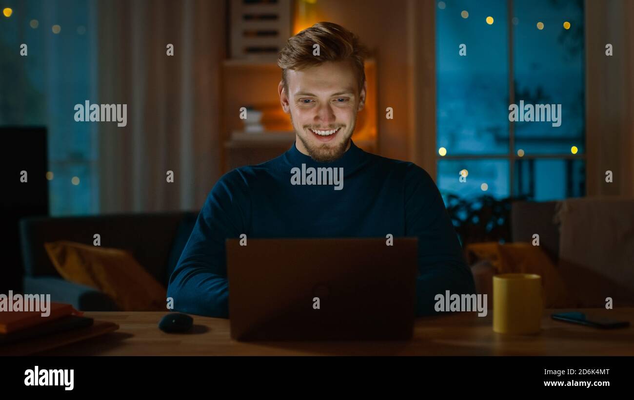 Handsome Smiling Man Works on a Laptop while Sitting at His Desk at ...