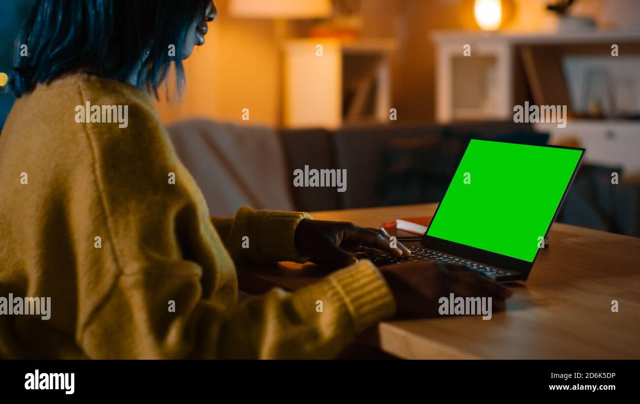 Beautiful Black Woman Sitting at Her Desk Works on a Laptop with Green ...