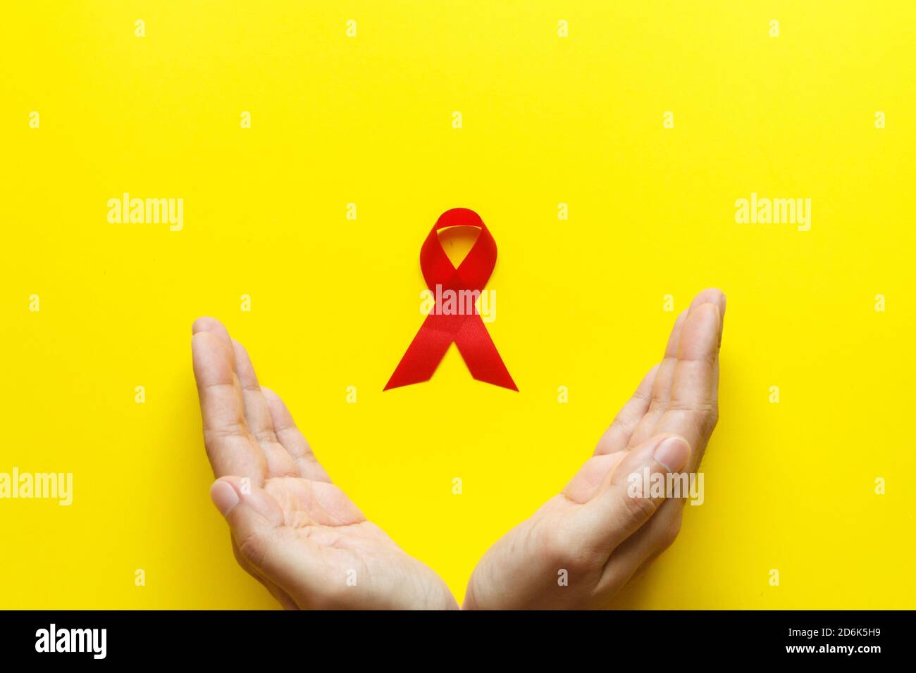 red AIDS awareness ribbon on yellow paper background. World aids day ...