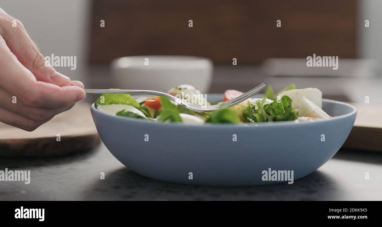 eat salad with avocado mixed salad leaves from a blue bowl on concrete ...