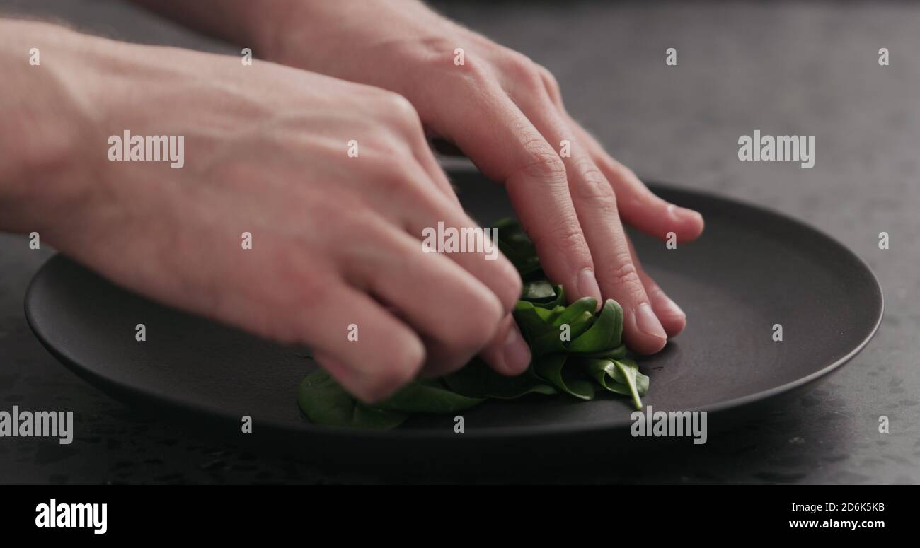 arrange spinach on black plate, wide photo Stock Photo - Alamy
