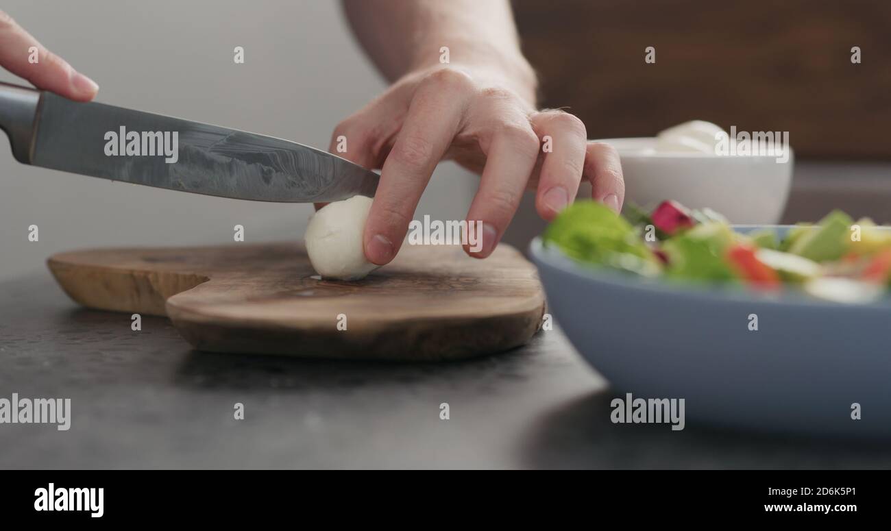 man cutting mozzarella balls on olive wood board, wide photo Stock ...
