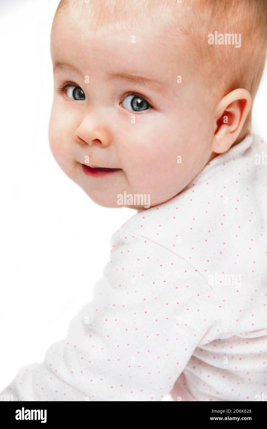 Side view of adorable smiling child with blue eyes looking at camera on ...