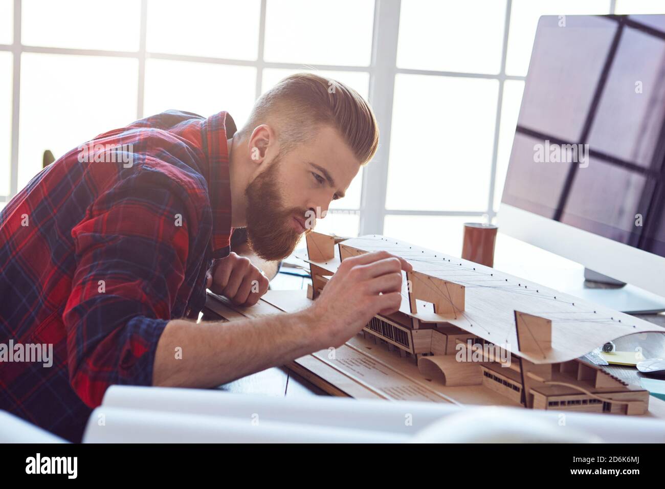 Young bearded man working around prototype of building in his office ...
