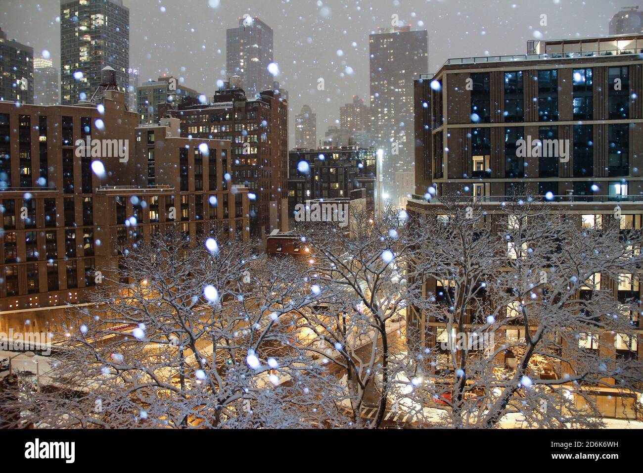 snowy hazy night in new york city with trees and buildings night time ...