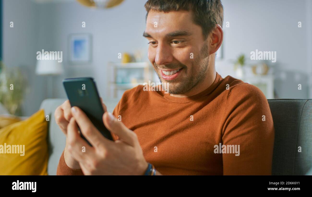 Portrait of Handsome Excited Man at Home Uses Smartphone. Man Relaxing ...