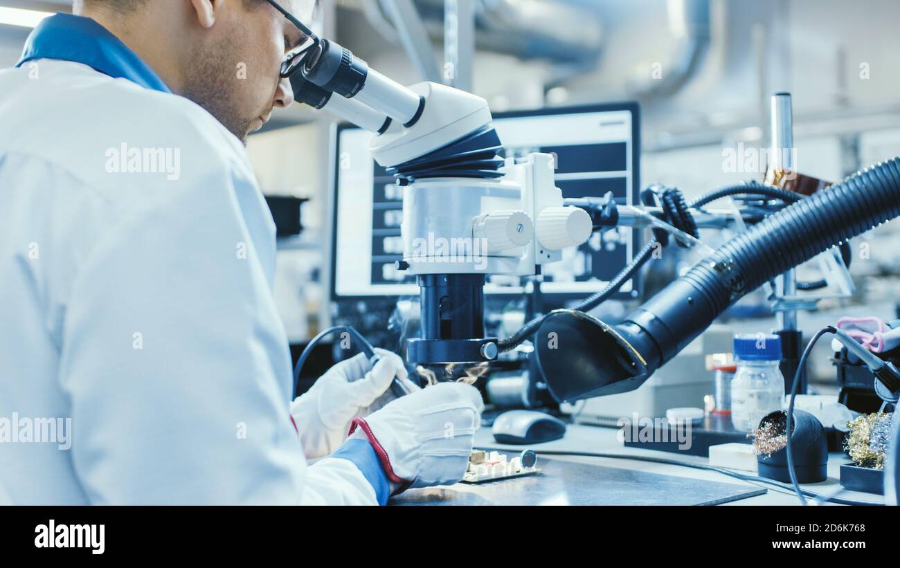 Electronics Factory Worker in White Work Coat is Soldering a Printed ...