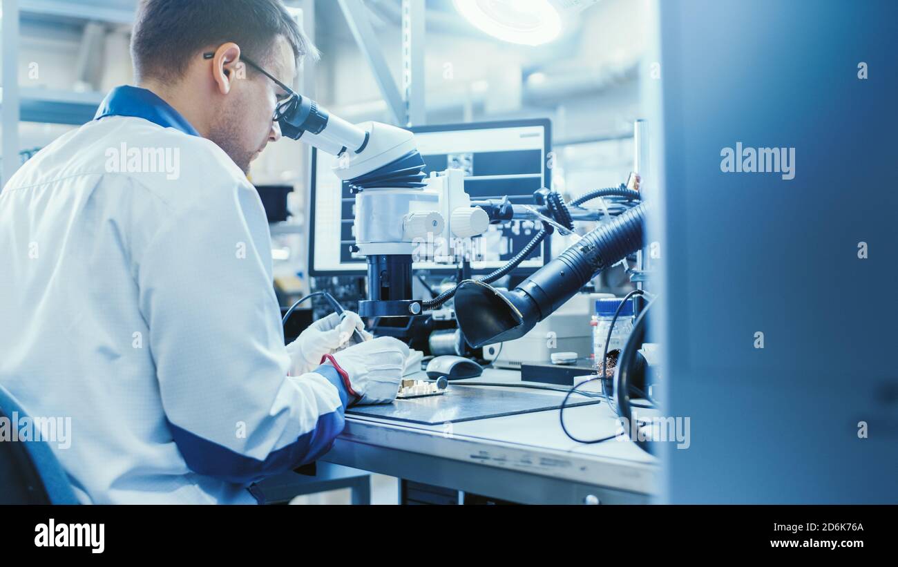 Electronics Factory Worker in White Work Coat is Soldering a Printed ...