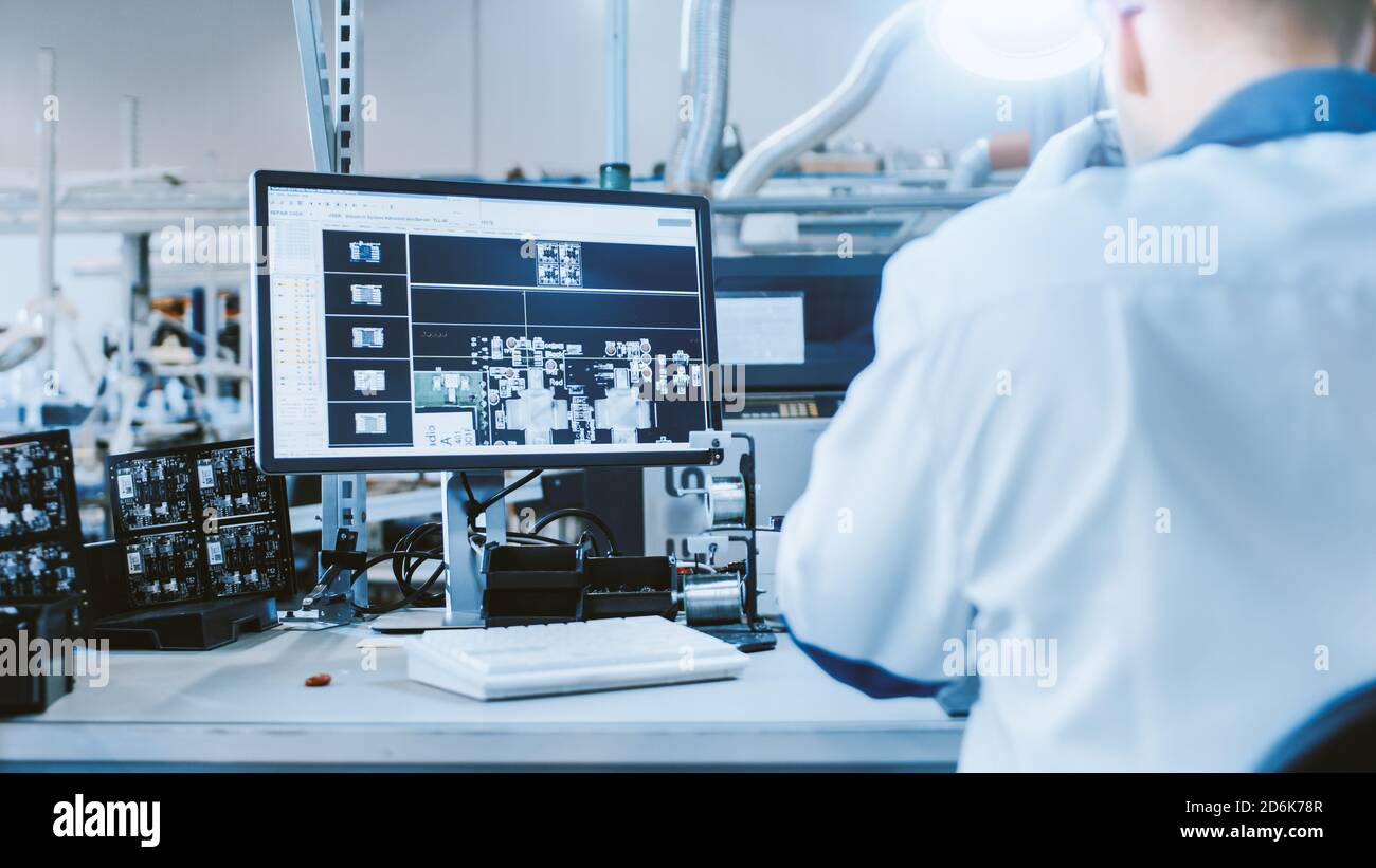 Electronics Factory Worker in White Work Coat Inspects a Printed ...
