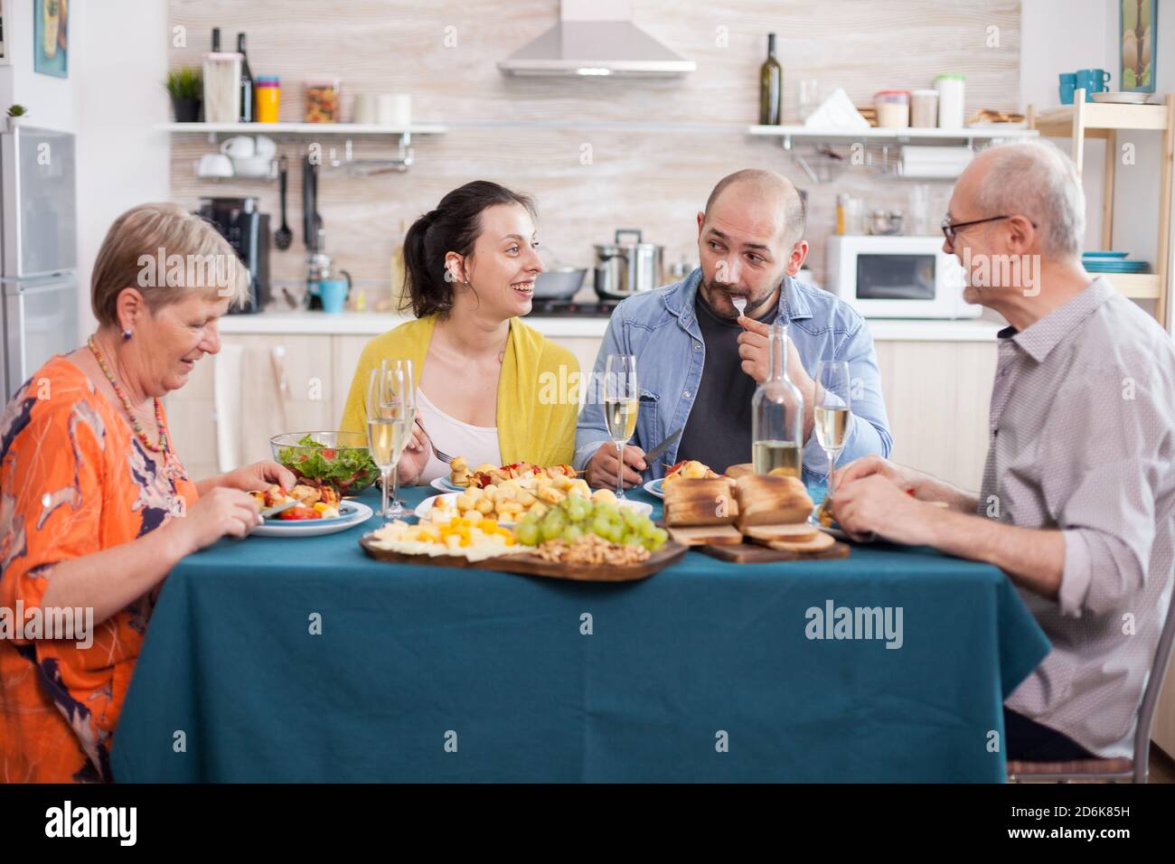 Daughter smiling at father in kitchen during family lunch. Man eating ...