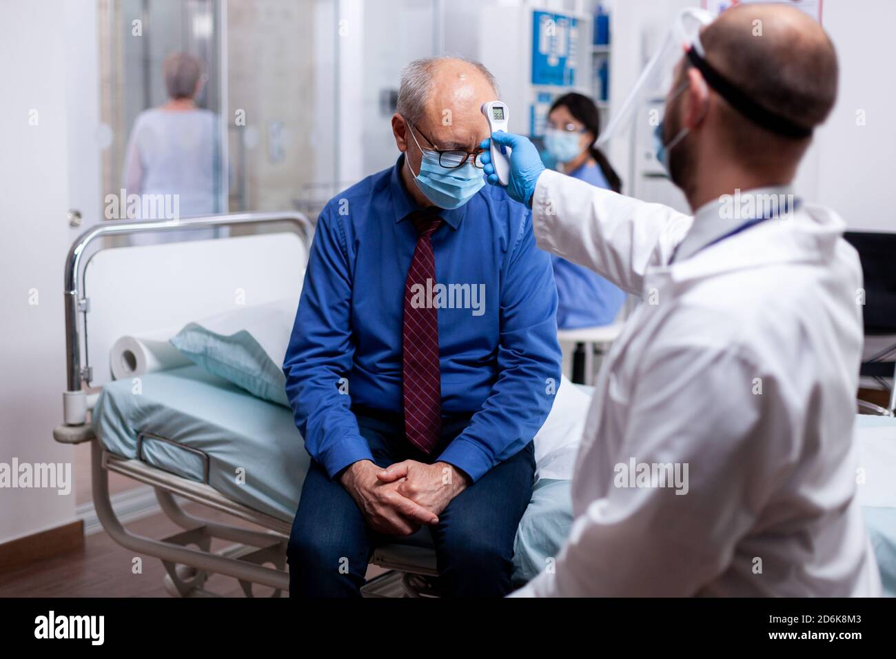 Doctor during examination of body temperature of senior patient in ...