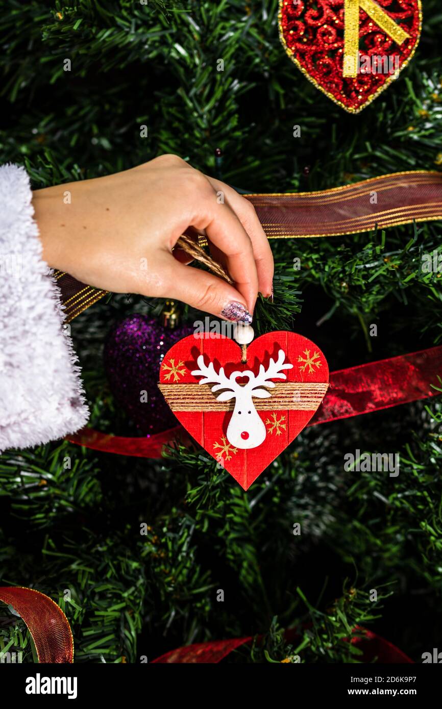 Decorating Christmas tree, hand putting Christmas decorations on fir ...