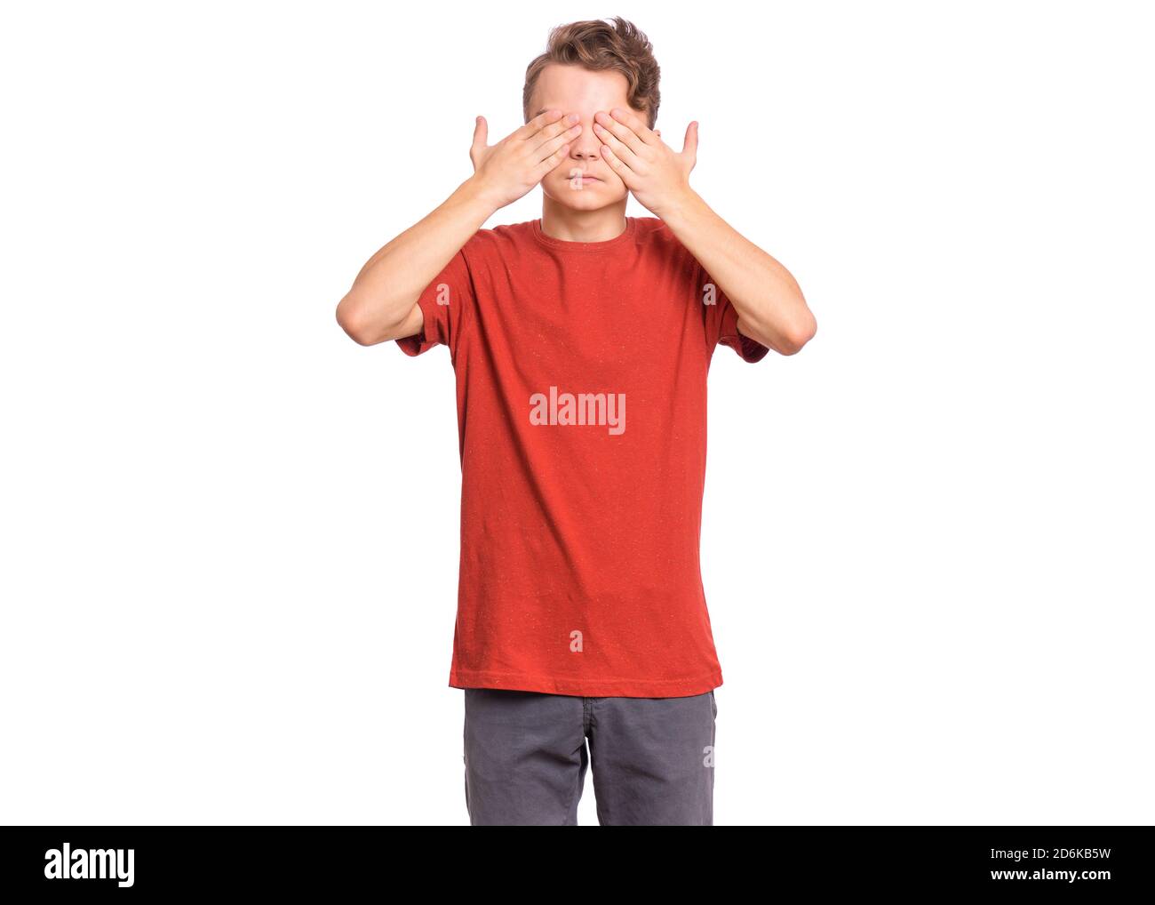 Handsome teen boy with sad expression covering face with hands while ...