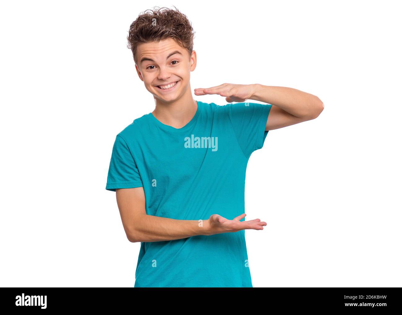 Handsome teen boy shows something in his hands and looking at camera ...