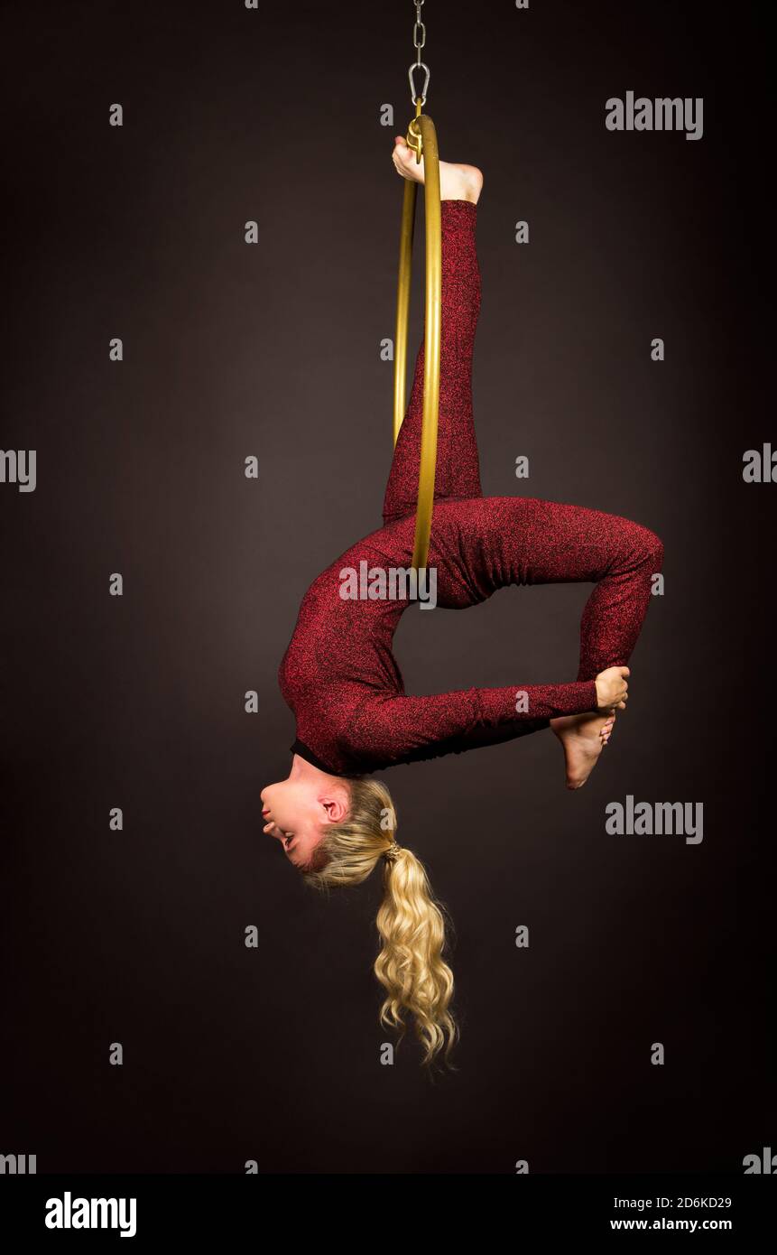 A slender blonde woman-an air acrobat in a red suit with long hair ...