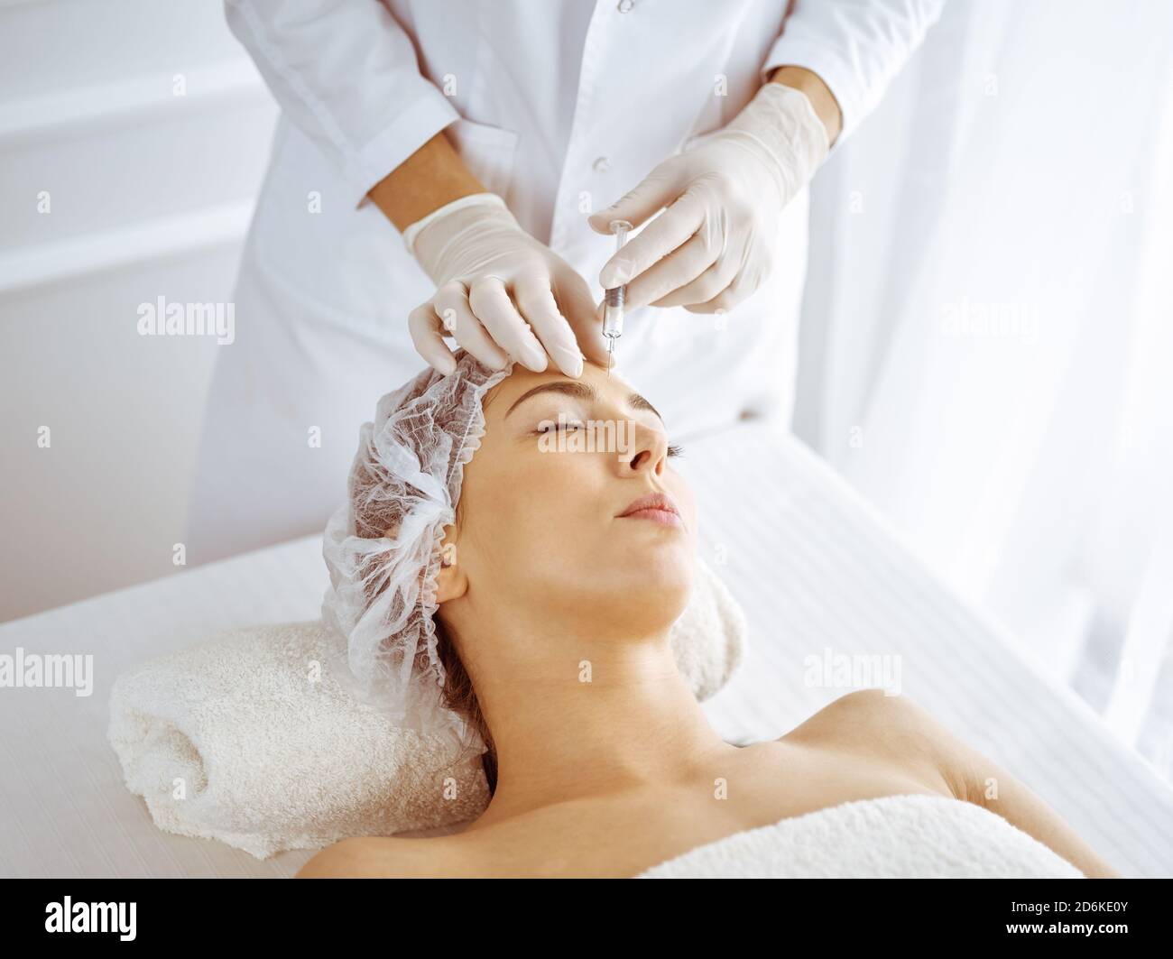Beautician doing beauty procedure with syringe to face of young ...