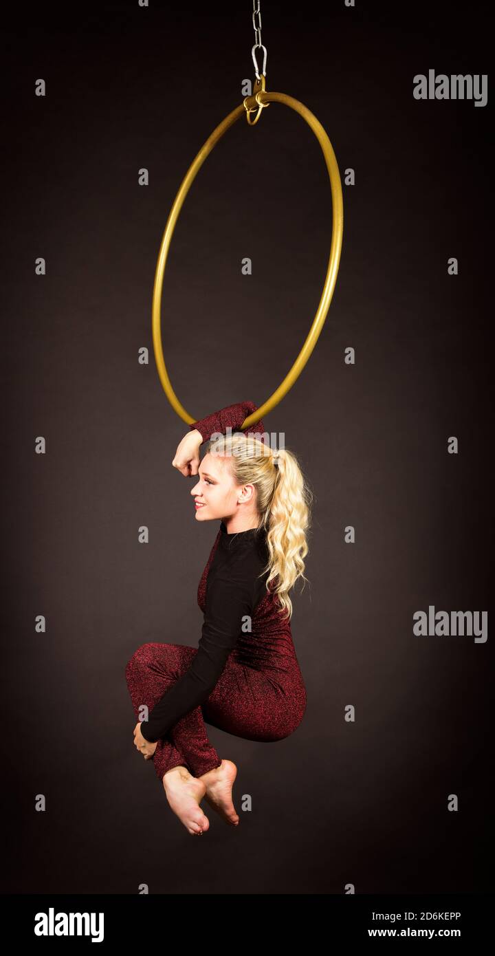 A slender blonde woman-an air acrobat in a red suit with long hair ...