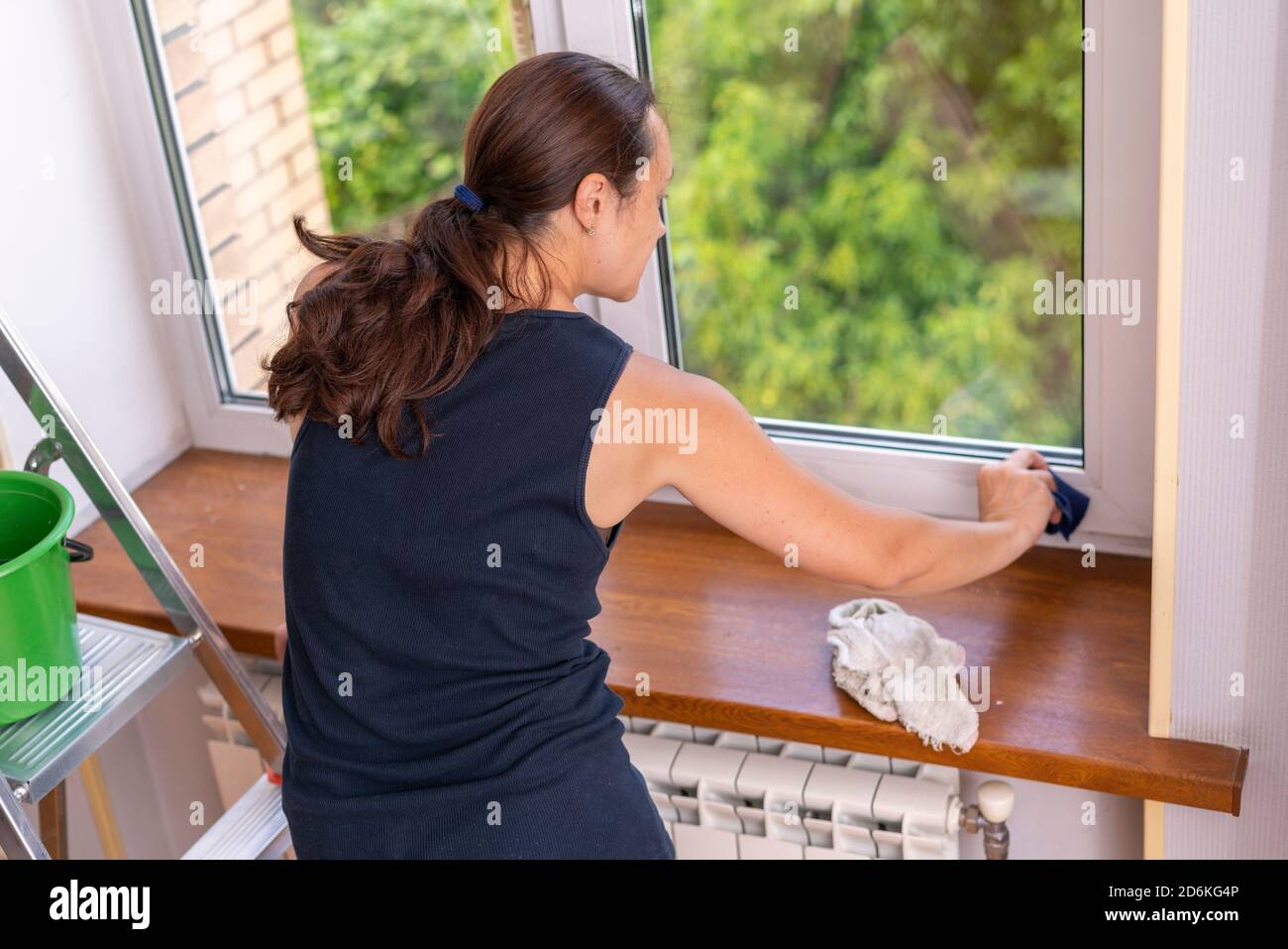 Back view of the young woman who washing the window with rag and window ...