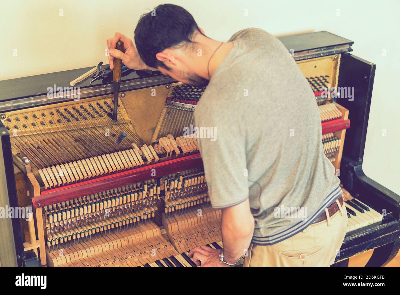 Piano tuning process. closeup of hand and tools of tuner working on ...
