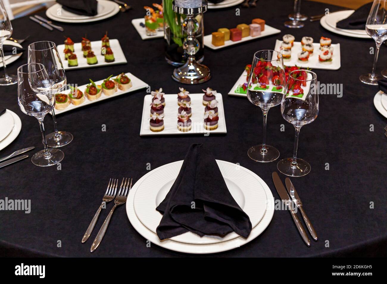 Round table with black tablecloth and black napkins, set of cutlery ...