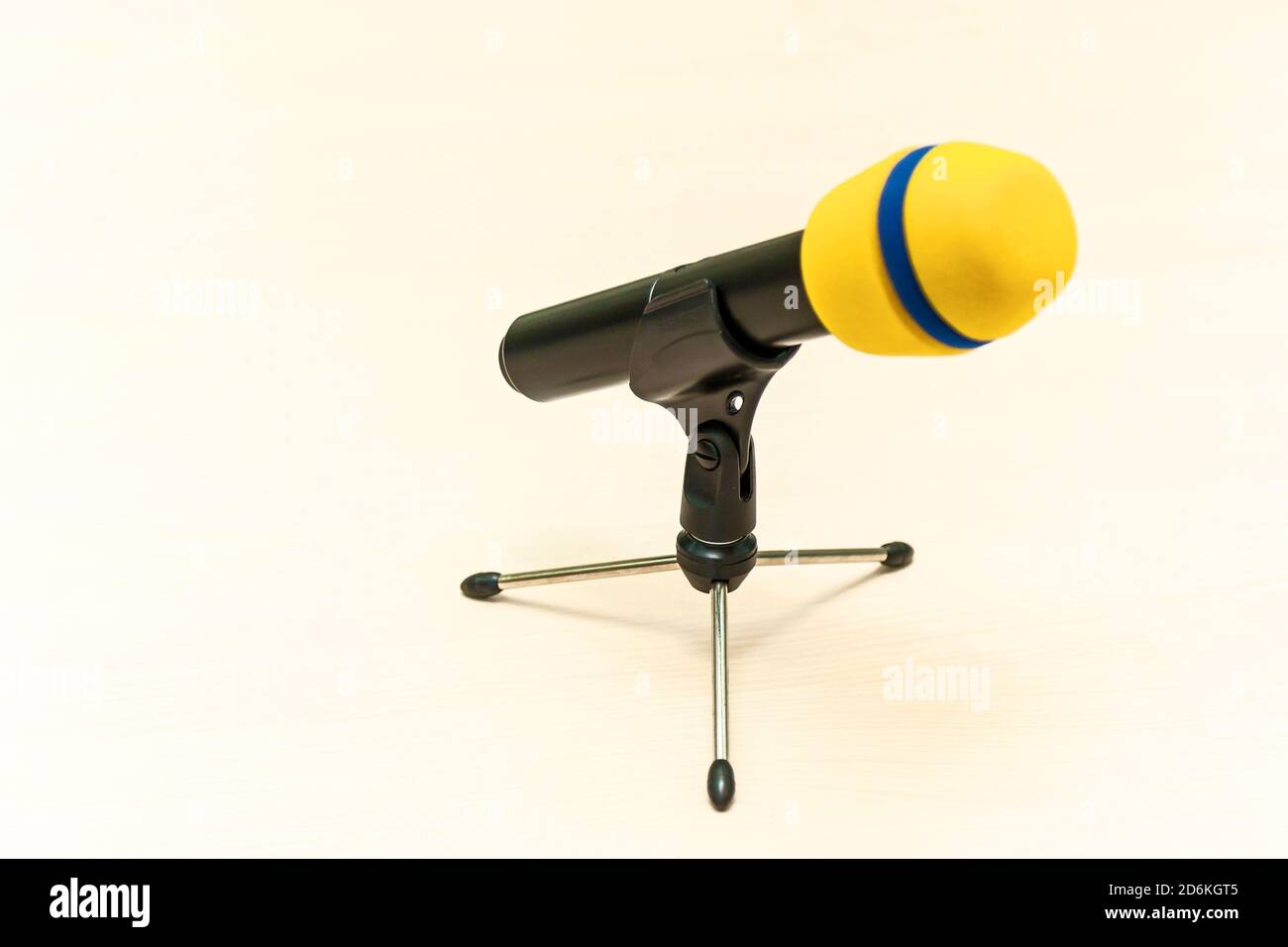 Wireless yellow microphone with stand on white table for speaking ...