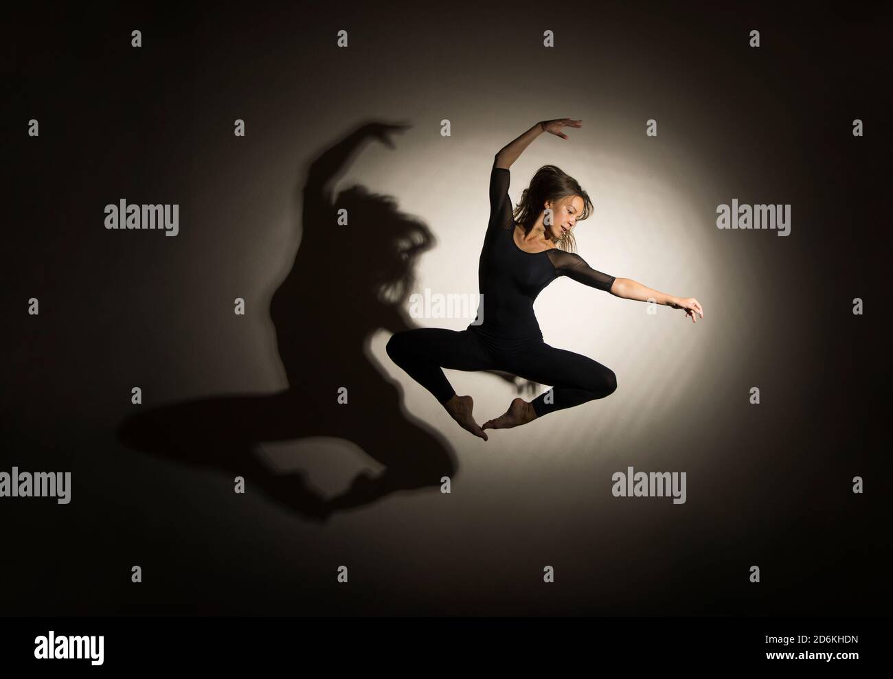 woman in dark performs gymnastic jumping, on a white background there ...