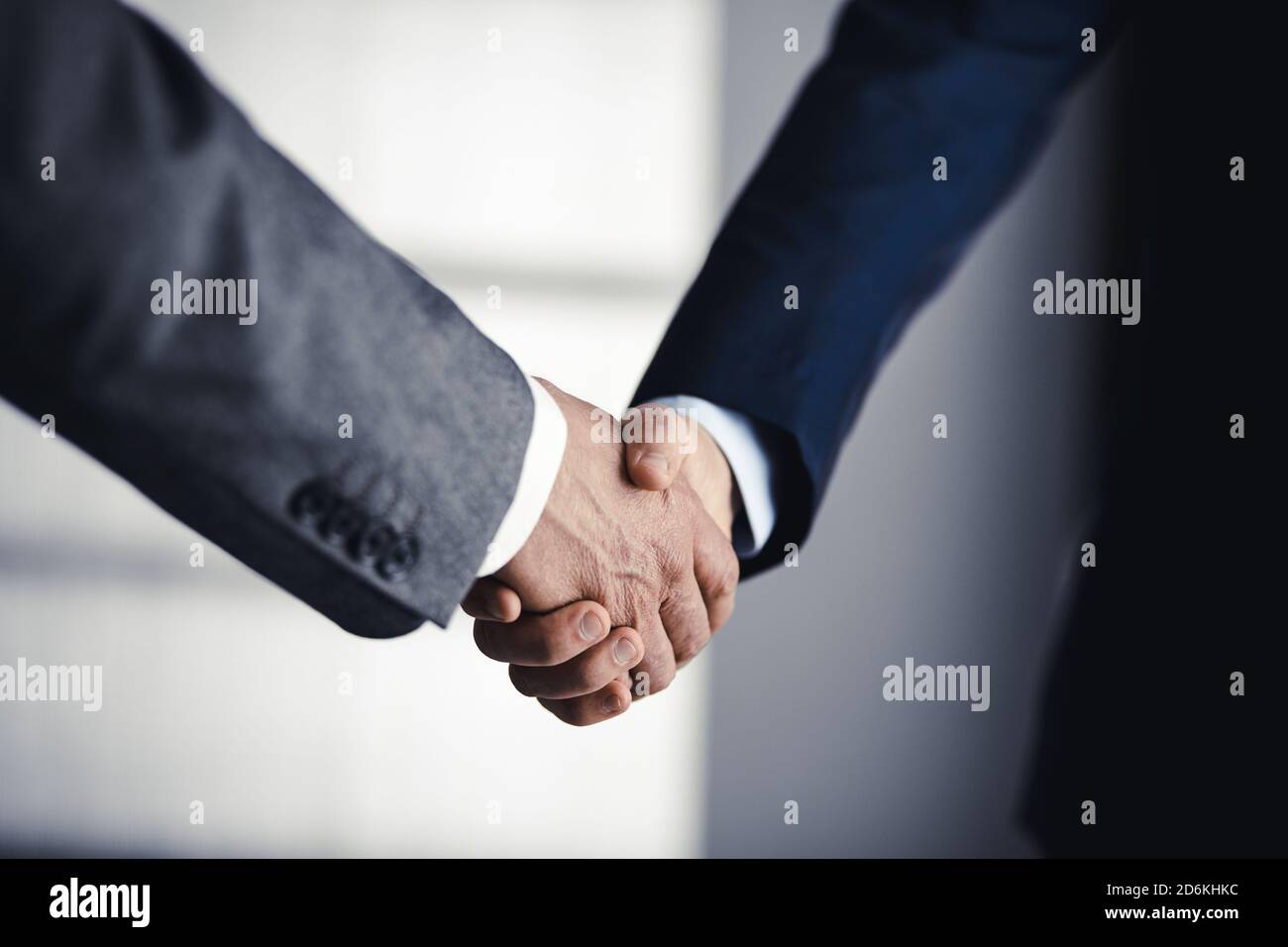Business people in office suits standing and shaking hands, close-up ...