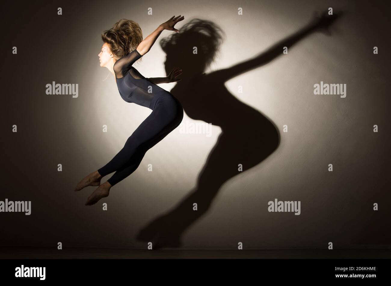 woman in dark performs gymnastic jumping, on a white background there ...