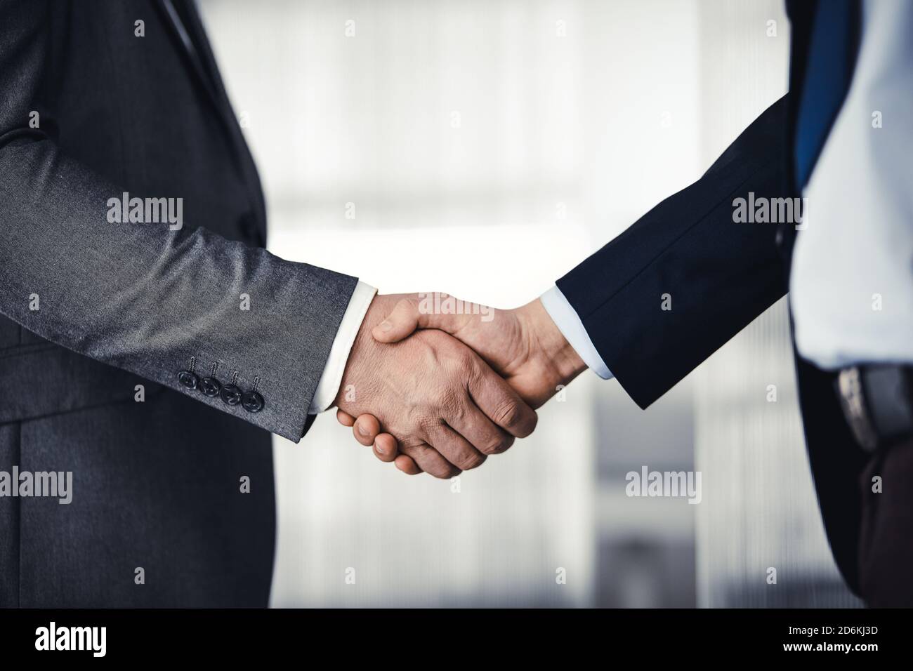 Business people in office suits standing and shaking hands, close-up ...