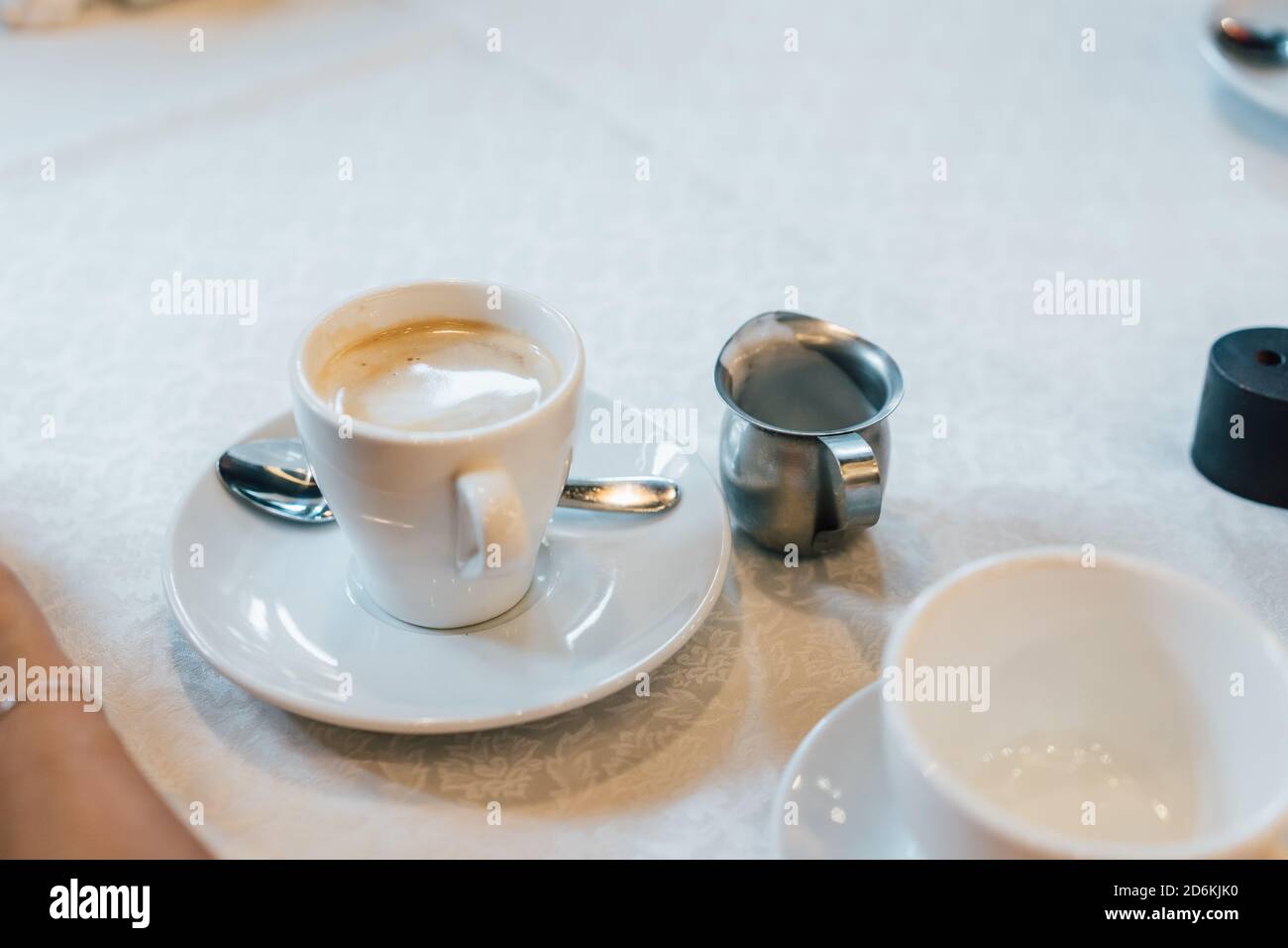 Small white cup of cappuccino stands on the table Stock Photo - Alamy